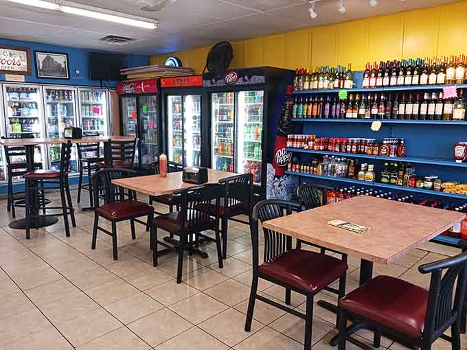 Bold blue walls, red cushioned chairs, and cold drinks stocked floor to ceiling; comfort lives here rent-free.