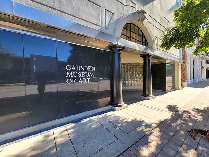 Elegant columns and polished black facades mark the Gadsden Museum of Art, where culture quietly holds its ground on a sunny sidewalk.