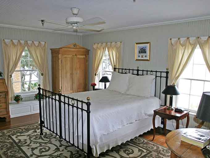 Crisp white linens, tall windows, and a wrought-iron bed frame. This room whispers "stay longer" in the most convincing way possible.