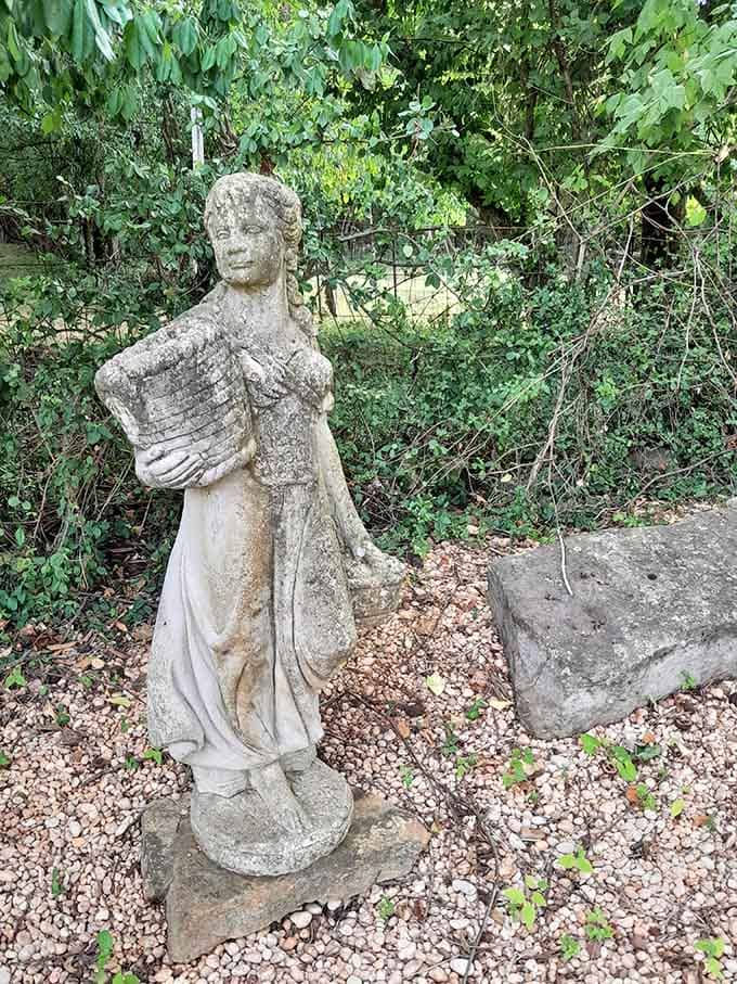 A weathered stone figure standing guard among the gravel, looking like she's been here since the beginning of time.