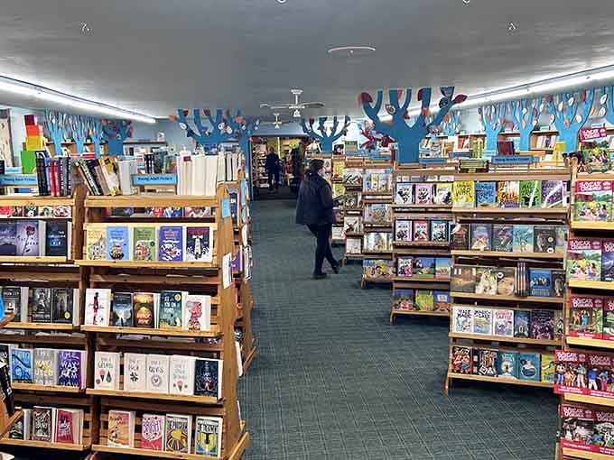 Overhead trees spread their branches across the bookstore ceiling, creating a literary forest where stories grow on shelves.