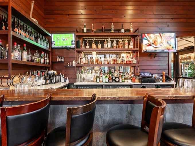 Shelves lined with bottles, warm wood paneling, and bar stools waiting patiently. This bar means serious, joyful business.