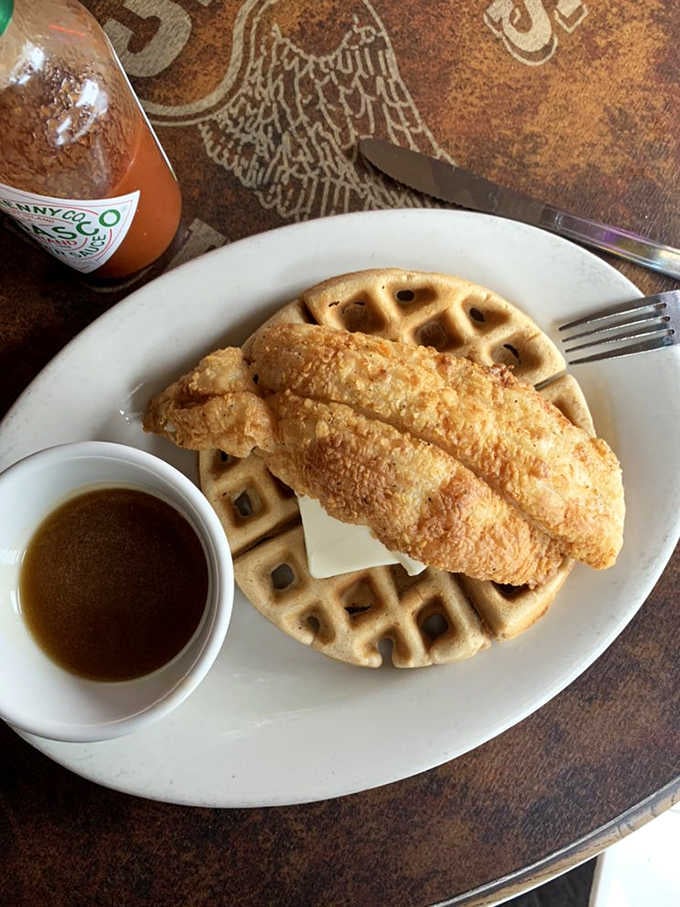 Fried catfish resting on a golden waffle with syrup on the side: breakfast, lunch, and dinner solved simultaneously.