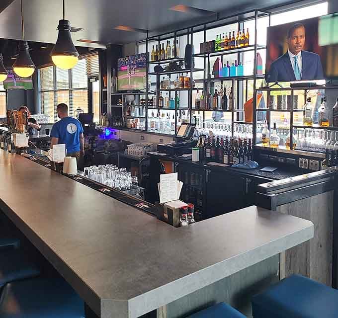 A well-stocked bar with glowing screens overhead, the kind of spot where good conversations start and great evenings take shape.
