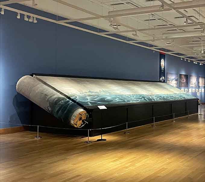 This massive rolled canvas depicting ocean waters stretches across the entire room. Some art simply refuses to be contained.