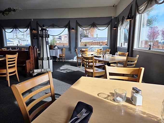 Warm afternoon light spills across neatly set tables and a decorative lighthouse, making this dining room feel like a quiet harbor all its own.