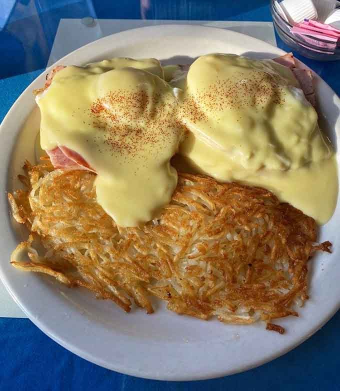 Eggs Benedict with hollandaise and a paprika finish, resting beside hashbrowns that are genuinely worth writing home about.