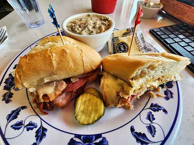 A sandwich stacked high with all the good stuff, served with a pickle and what appears to be excellent company.
