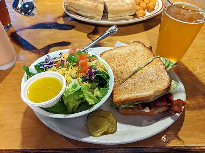 A classic BLT on toasted bread with a fresh side salad and a cold beer, the holy trinity of lunch.