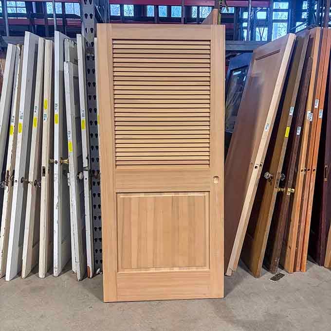 A beautiful louvered wood door leaning among its peers, solid craftsmanship that no flat-pack alternative could ever hope to match.