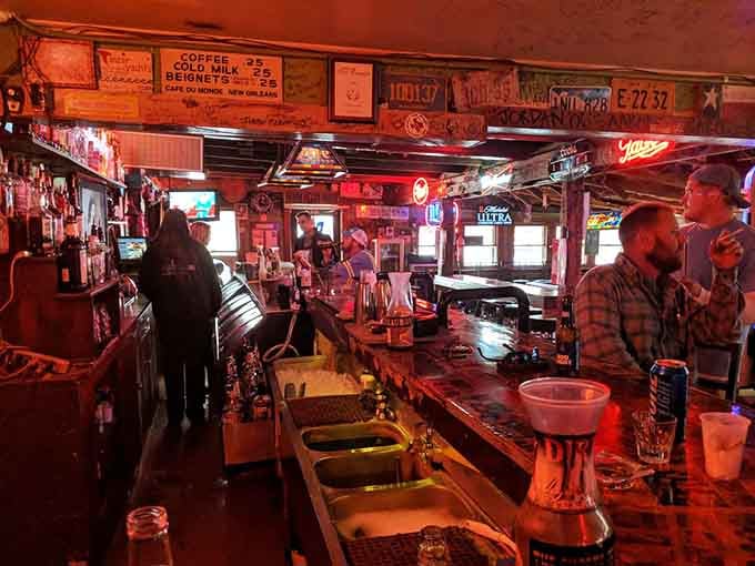 A long bar bathed in warm red light, lined with bottles and decades of good conversation. Pull up a stool.