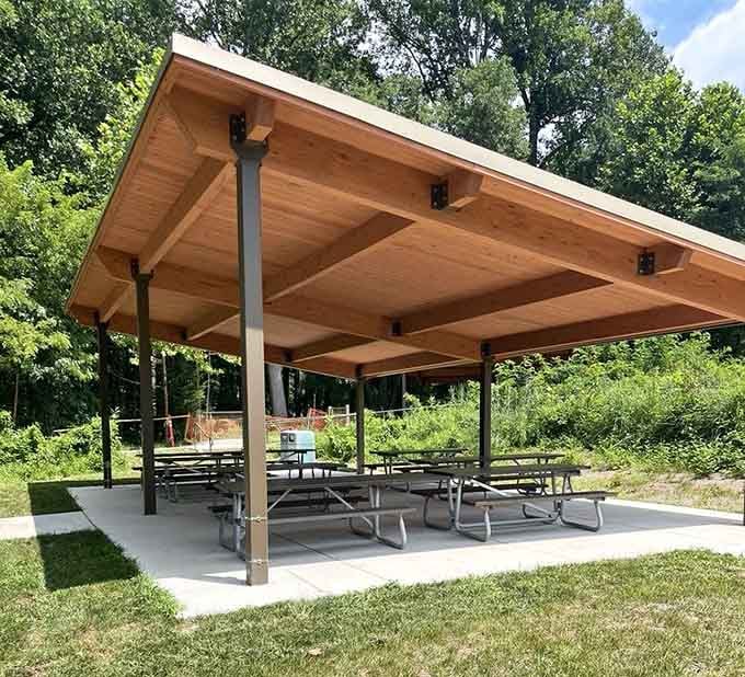A covered picnic shelter surrounded by trees. Pack a lunch, claim a table, and pretend you planned this all along.