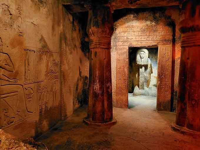 Dimly lit passages, carved columns, and a glowing statue at the end, this tomb replica is the real star of the show.