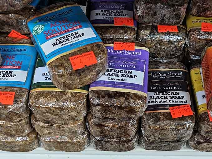 Chunky bars of natural African black soap in lavender, charcoal, and tea tree, a whole skincare philosophy stacked neatly on one shelf.