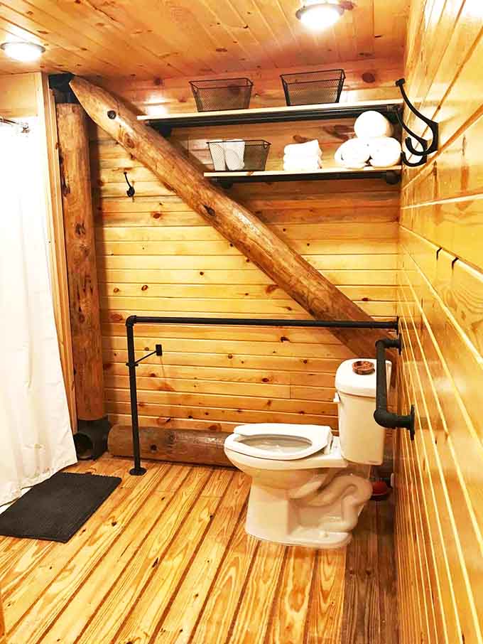 Open shelving, rolled towels, and a log beam cutting right through the bathroom. Rustic meets thoughtful.