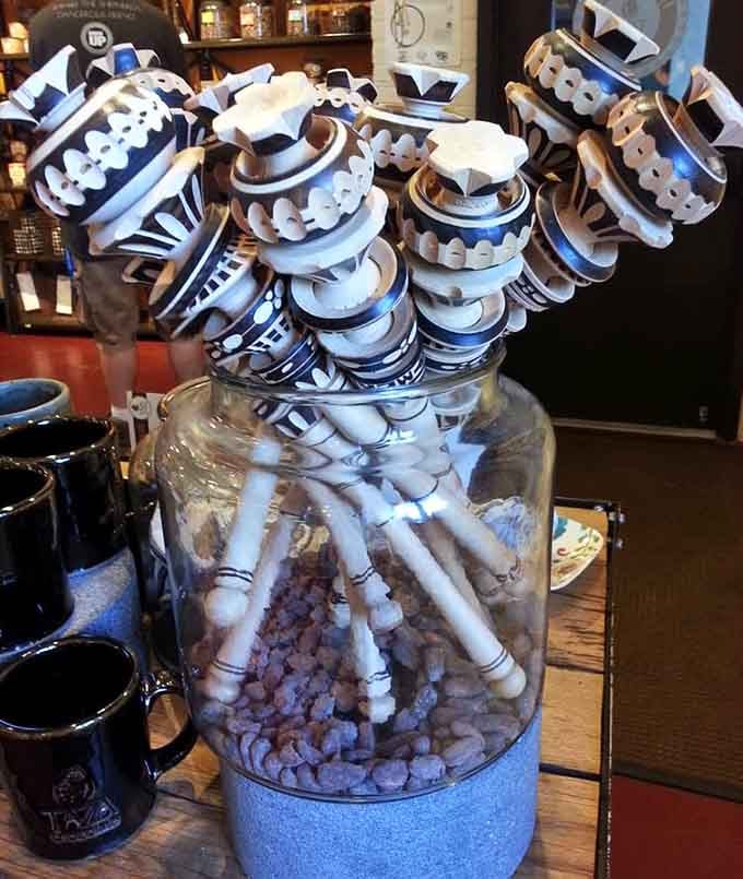 Traditional wooden molinillo whisks displayed in a glass jar, the elegant tool behind every perfect cup of Mexican drinking chocolate.