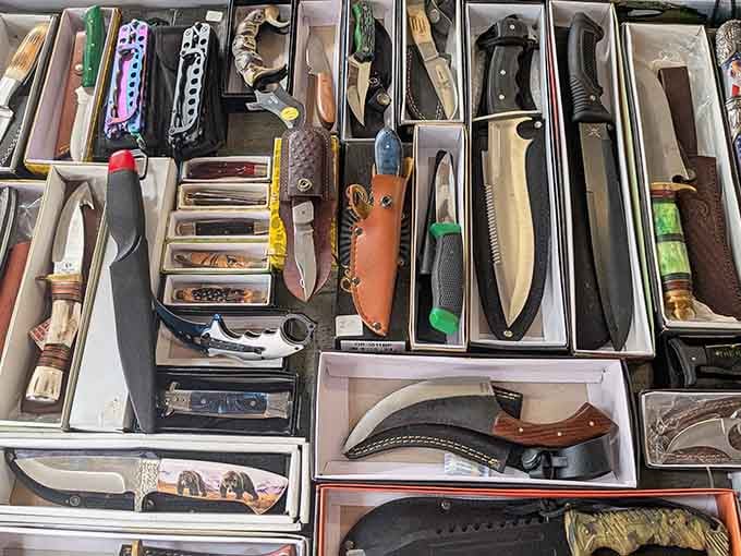 Dozens of blades lined up in neat rows like a very serious cutlery convention, pocket knives to hunting knives, all present and accounted for.