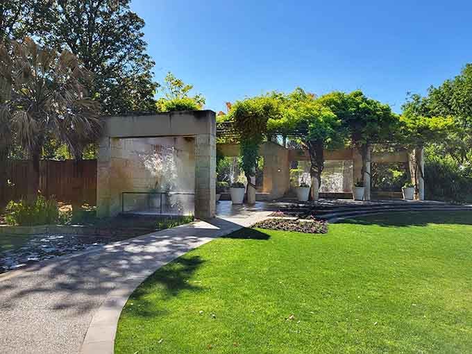 Stone columns draped in greenery and water features create a garden room that feels both grand and peaceful.