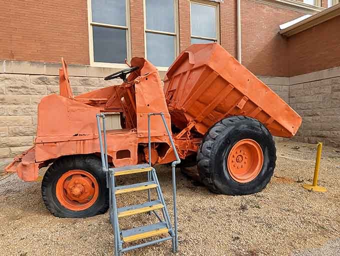 This bold orange dump truck has clearly earned its retirement, sitting proudly outside like a well-decorated veteran.