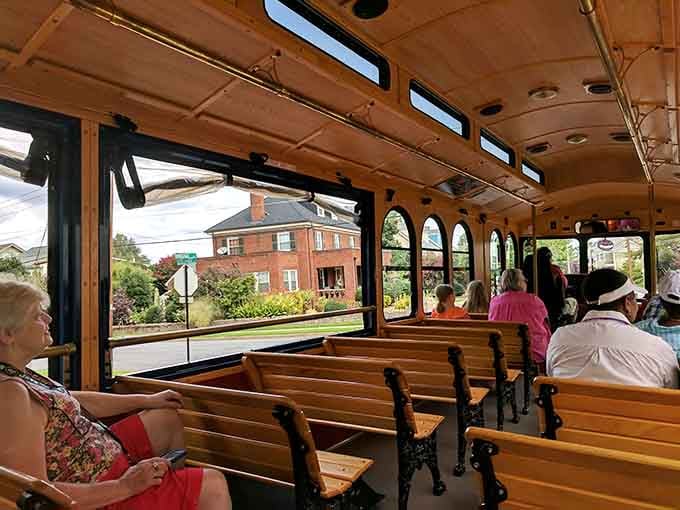 Passengers settle into wooden benches as a gorgeous brick colonial home drifts past the open window like a living postcard from another century.