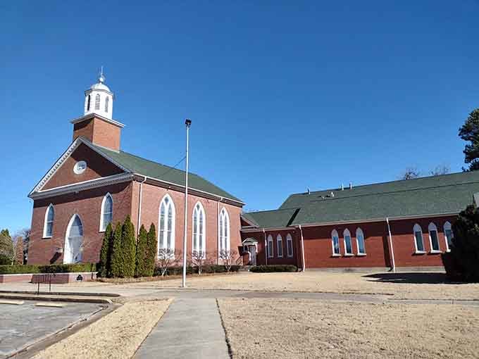 Red brick, Gothic windows, and a white steeple reaching skyward, this church means business in the most peaceful way possible.