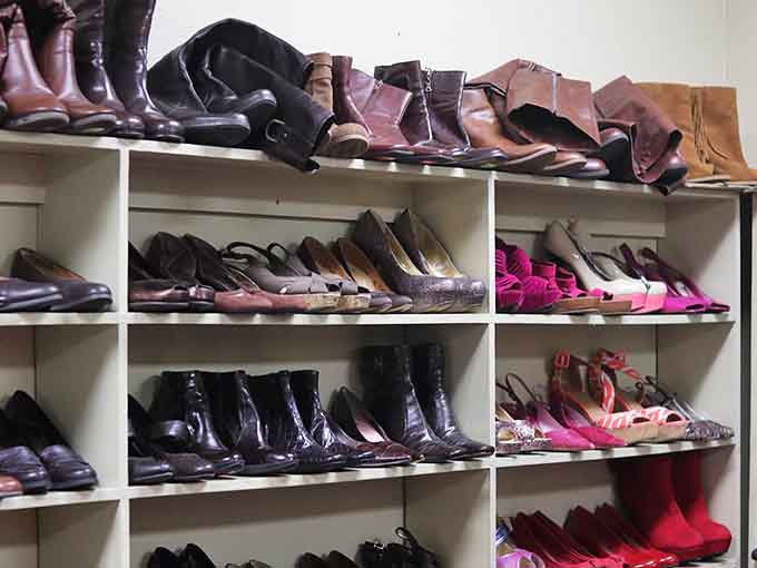 Boots, heels, flats, and sandals packed onto shelves, because Cinderella clearly donated to the right place.