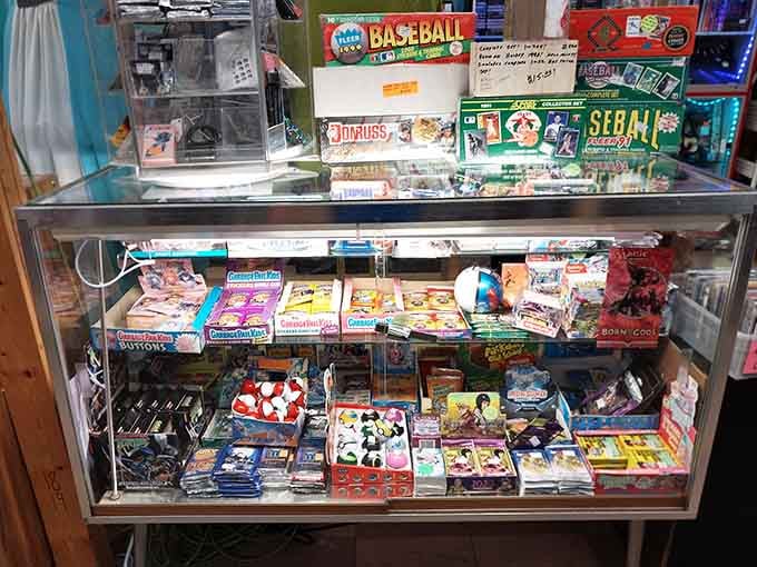 A glass case packed with vintage baseball cards and Garbage Pail Kids, childhood nostalgia hitting all at once.