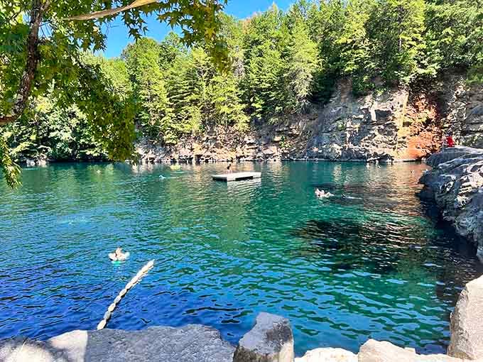 That emerald swimming hole surrounded by granite walls transforms an old quarry into a refreshing summer paradise.