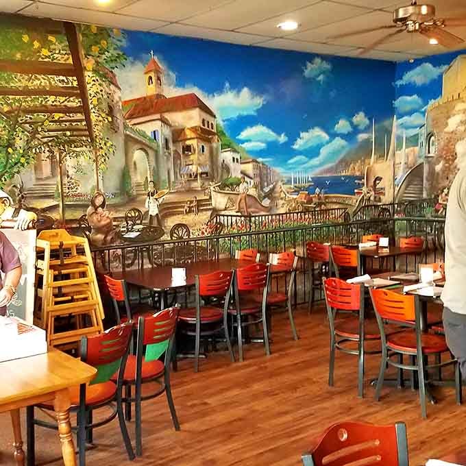 Vibrant murals of Italian coastal life stretch across the walls, turning every meal into an accidental mini-vacation to the Mediterranean.