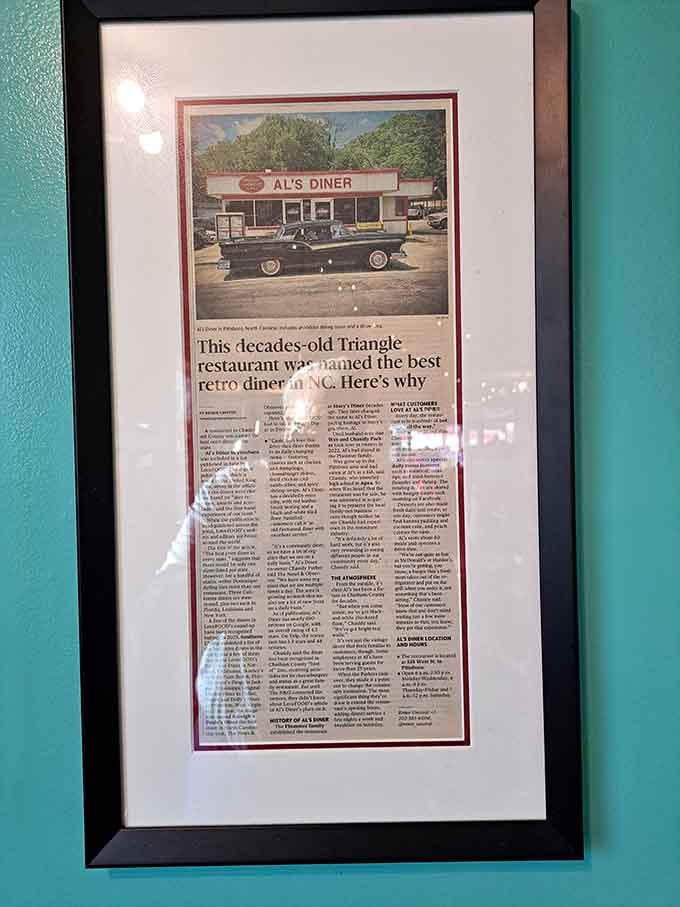 A framed newspaper article on the teal wall, because some compliments deserve to be permanent fixtures.