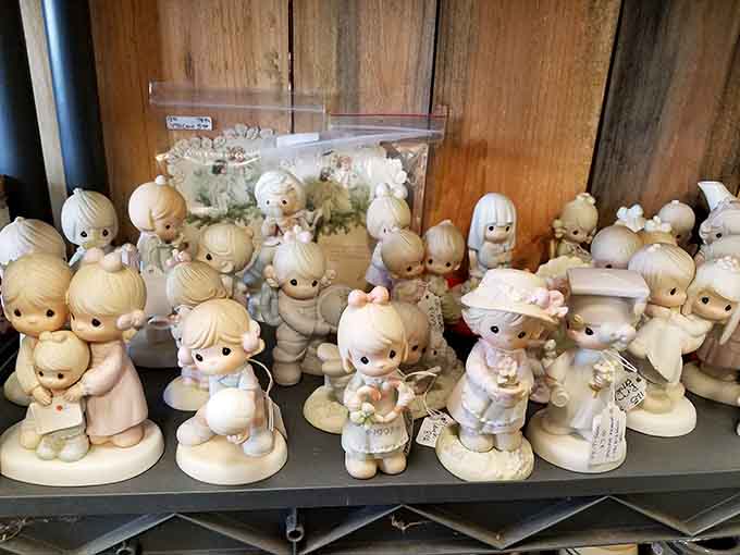A whole shelf of Precious Moments figurines, each one radiating the kind of gentle nostalgia that makes you call your mom.