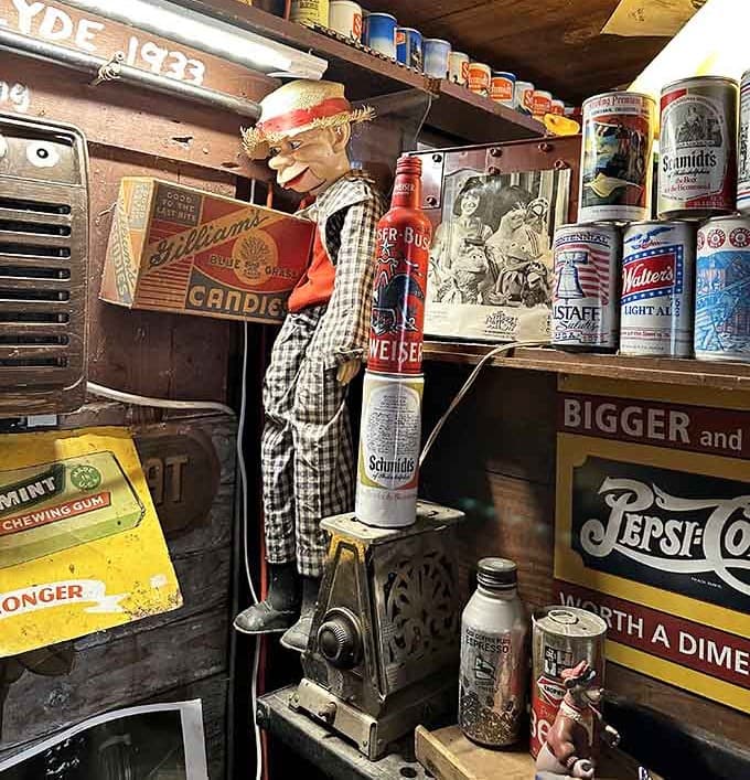 A ventriloquist dummy climbing a vintage coffee grinder surrounded by old beer cans, completely normal Tuesday in Calvert City.