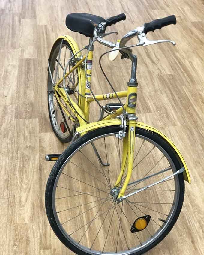 A cheerful yellow vintage bicycle that looks like it belongs in a feel-good movie about summer adventures.