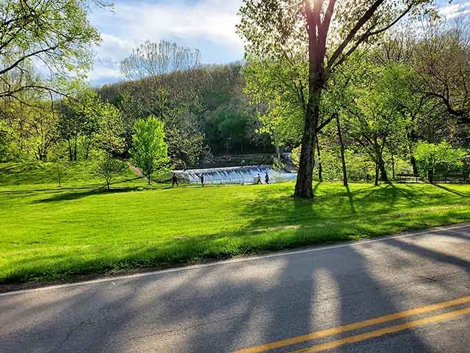 Spring sunlight spilling across that rolling green lawn with the spillway shimmering beyond &mdash; honestly, a painting owes this view royalties.