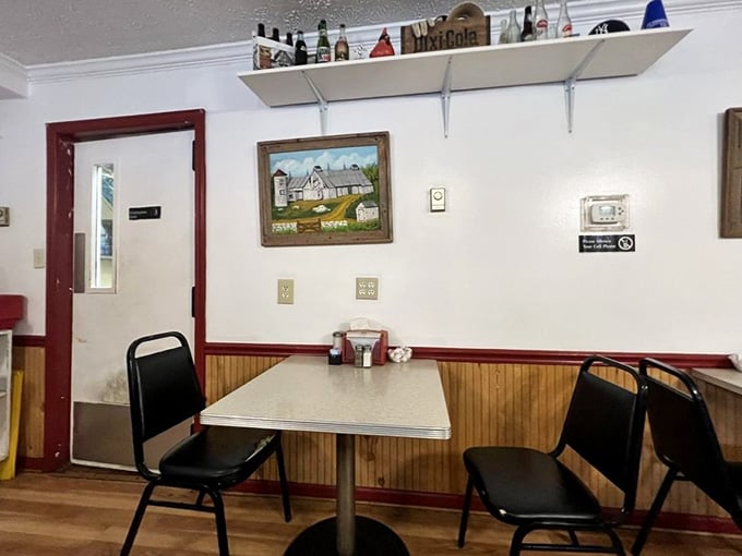 A corner table for two, a folk art painting of a farmhouse on the wall, and vintage bottles overhead. Quietly perfect.