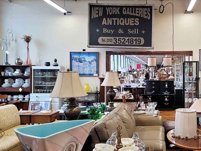 A hanging "New York Galleries Antiques" sign presides over lamps and sofas like a very distinguished landlord.