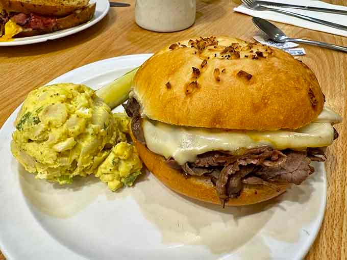 A beautifully loaded sandwich on a seeded Kaiser roll, paired with creamy potato salad, this plate is pure deli perfection.