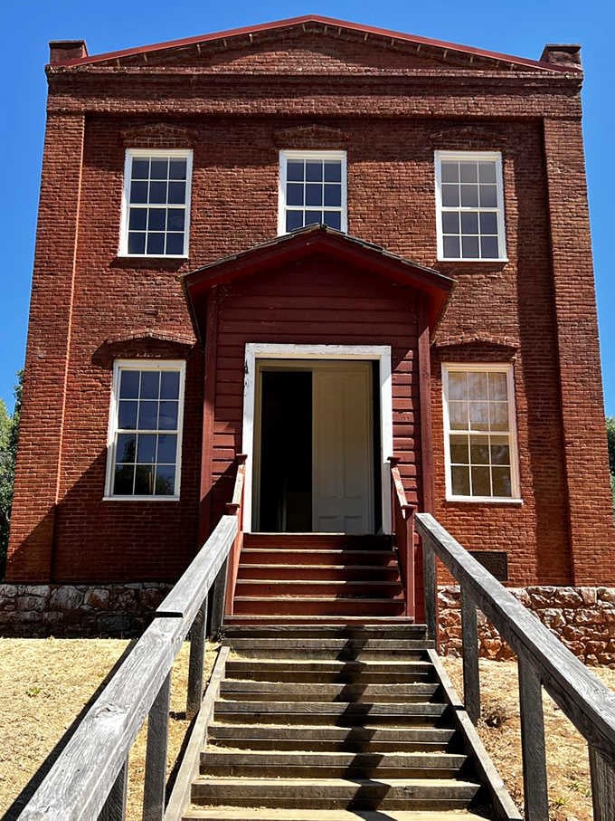 That brick schoolhouse has more character in its wooden steps than most modern buildings have in their entire existence.