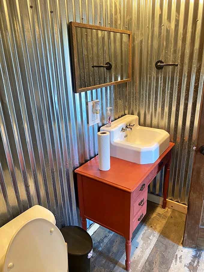 Corrugated metal walls, a red vanity, and a classic white sink. Rustic never looked this pulled together.