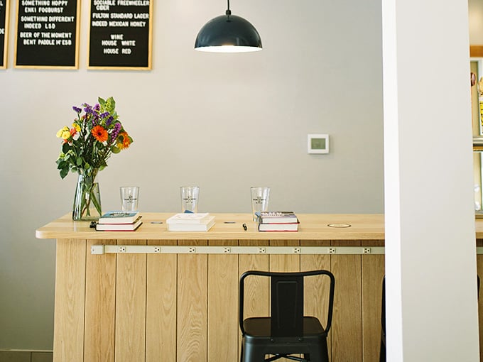 A clean wooden bar, fresh flowers, and a beer menu on the wall. Yes, this is still a bookshop. A very good one.