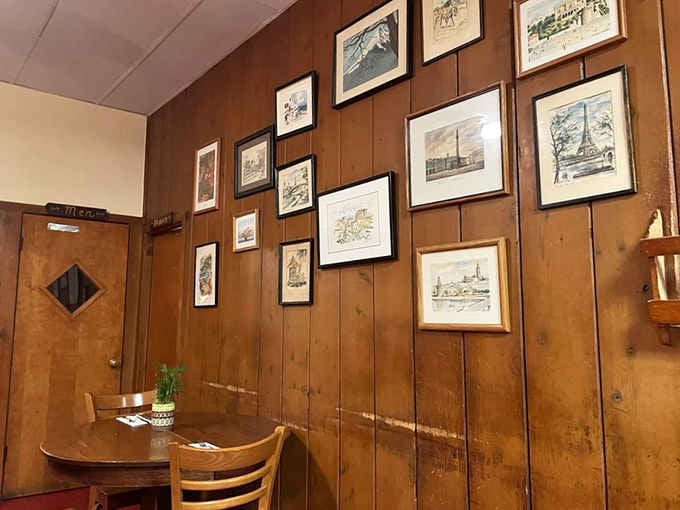 Framed sketches covering the wood-paneled wall, from mountain scenes to the Eiffel Tower. Someone here has excellent taste.