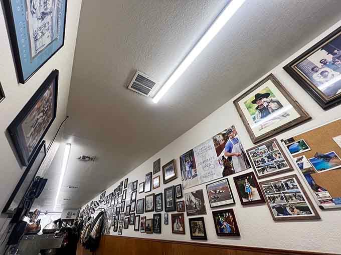 Dozens of framed photos climbing toward the ceiling, a community's memory preserved one snapshot at a time, better than any museum.