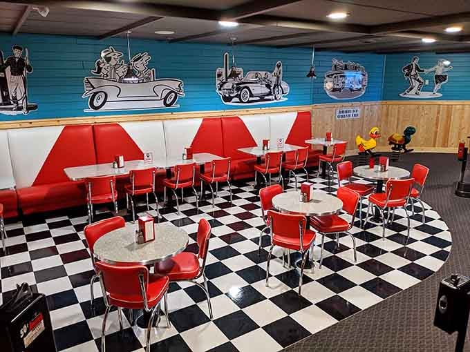 Black-and-white murals of dancers and convertibles stretch across teal walls in this cheerful, retro dining room.