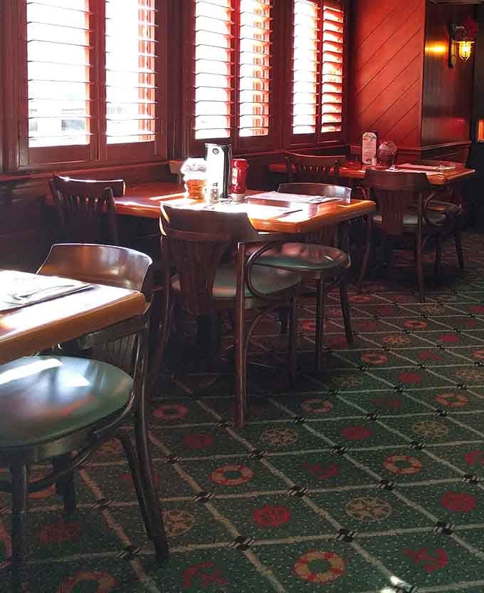 Plantation shutters filter afternoon light across patterned carpet and dark wood, giving this dining room a timeless, comfortable character.