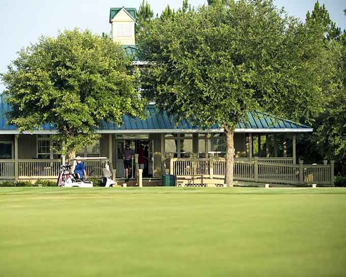 The golf clubhouse sits behind a carpet of green so perfect it looks like someone ironed it before your arrival.