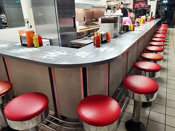 A long row of red stools at a steel counter. This is where the real regulars sit and the good stories happen.