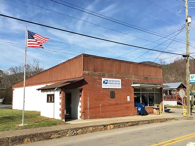 The Hot Springs Post Office stands proudly, American flag flying, mountains rising quietly behind it.