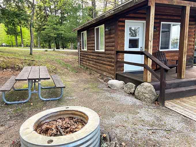 A cozy log cabin with a fire ring and picnic table. Roughing it never looked this inviting.