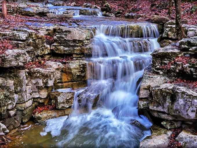 Cascading waterfall flowing over tiered rocks like liquid staircase, proving Mother Nature studied architecture before creating this masterpiece.