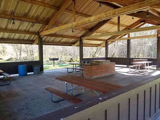 A covered picnic shelter with a central fireplace, the kind of spot that makes a rainy day feel like a feature, not a problem.